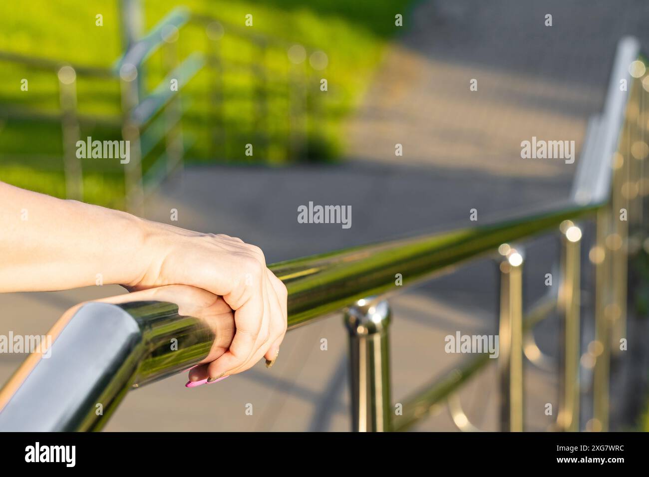 woman's hand holding onto the metal staircase railing. metal handrail ...