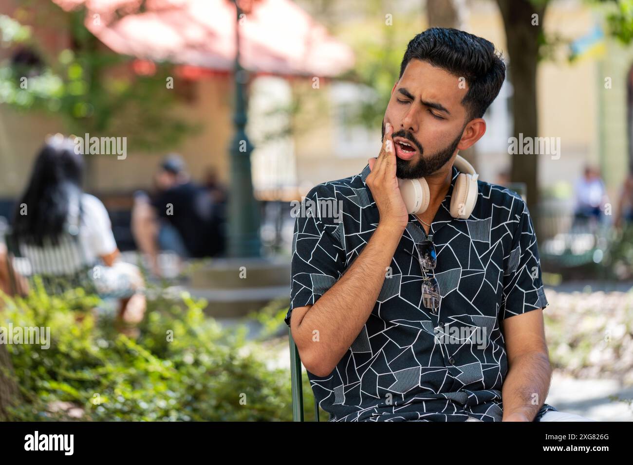 Dental problems. Frustrated sick ill Indian man tourist touching cheek ...