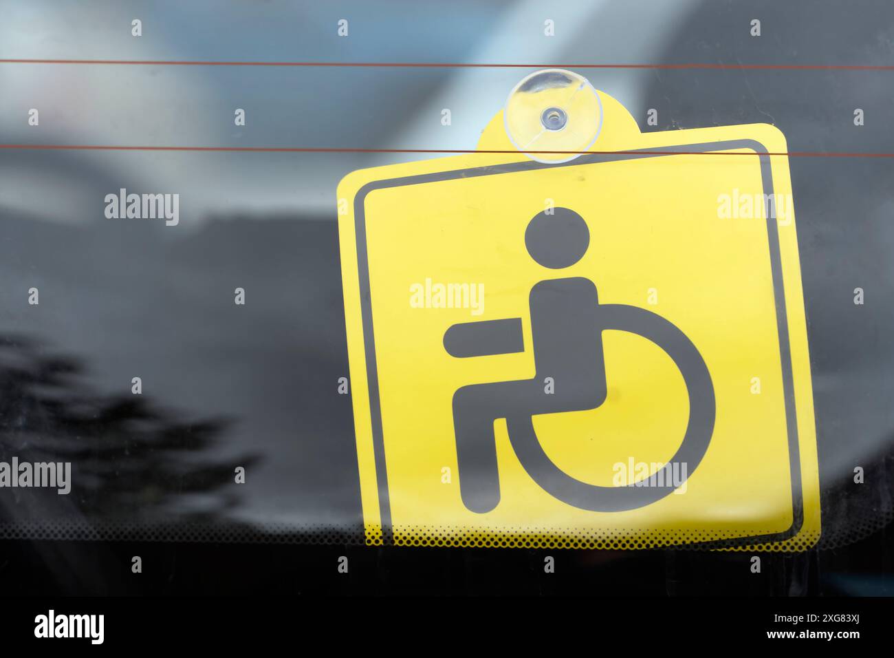 Close-up of a yellow accessible parking permit on a vehicle window ...