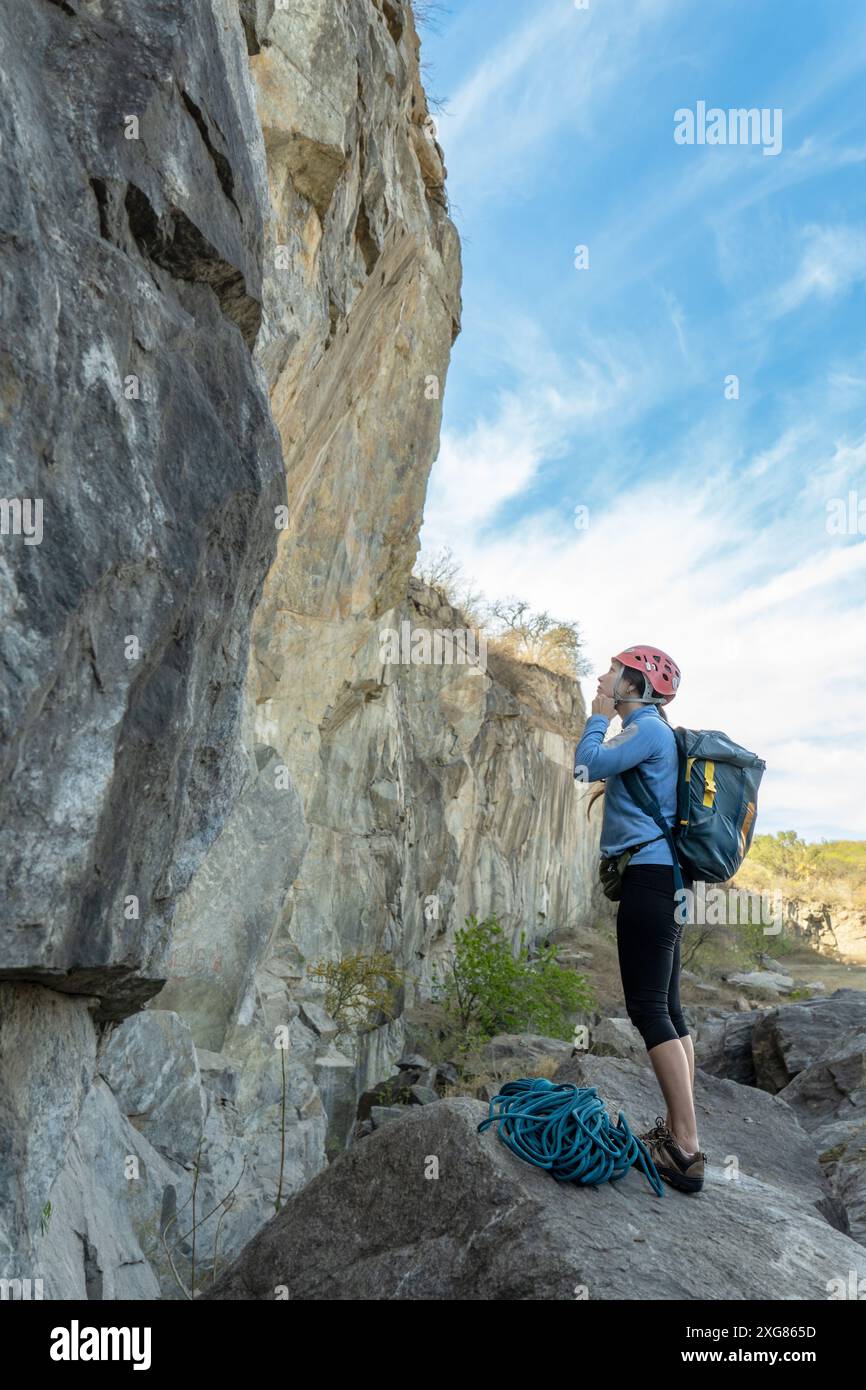 Brave female hiker standing on cliff edge, adjusting safety helmet with ...