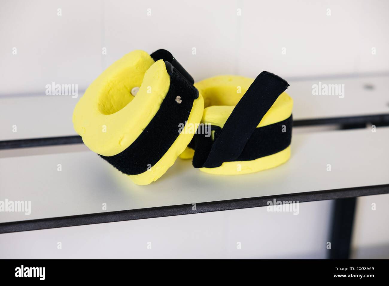Two yellow foam arm floaters with black straps resting on a bench in an ...