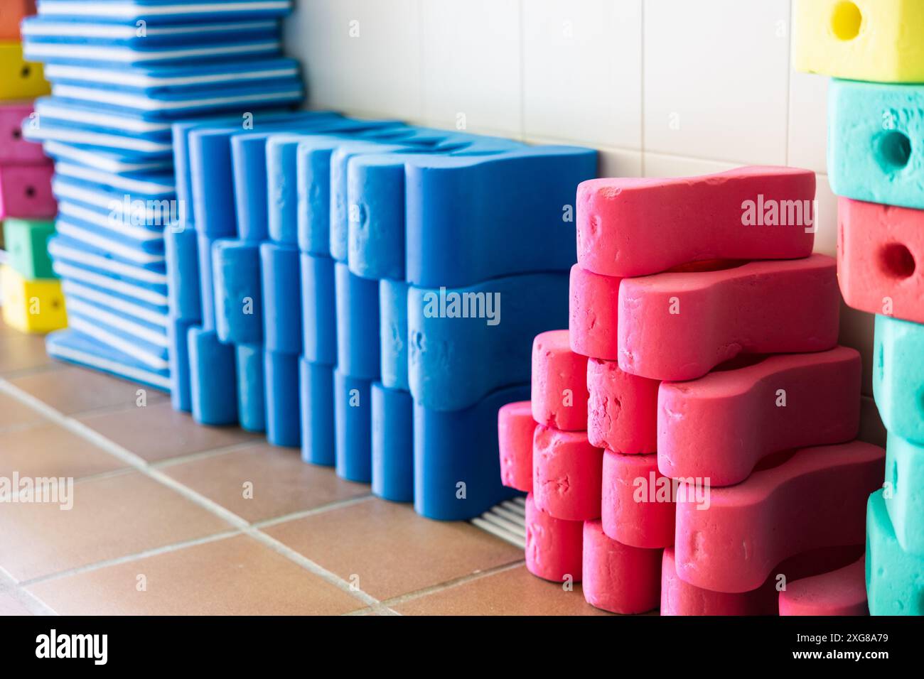 Brightly colored foam floaters stacked neatly on the floor of an indoor ...