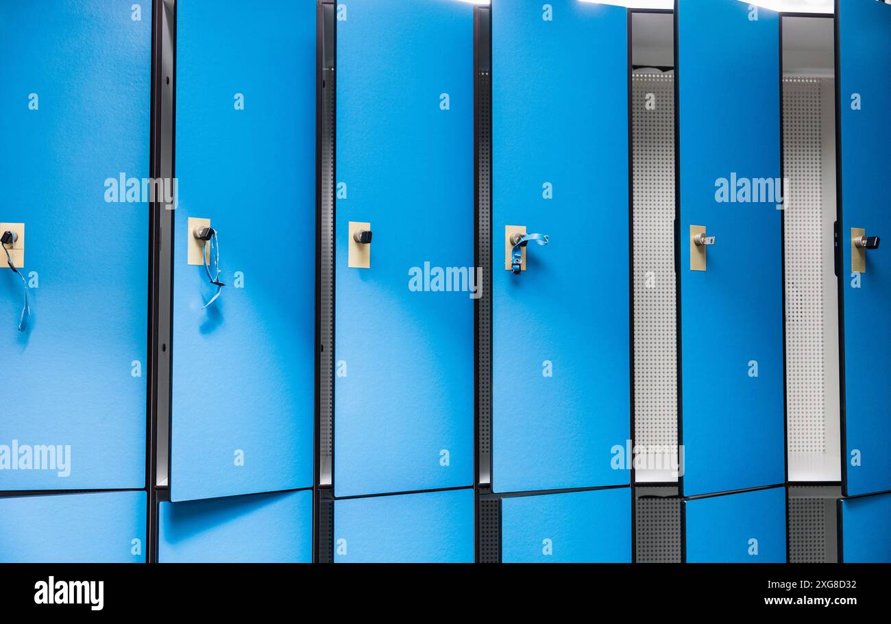 Row of blue lockers with open doors in an indoor pool changing room ...