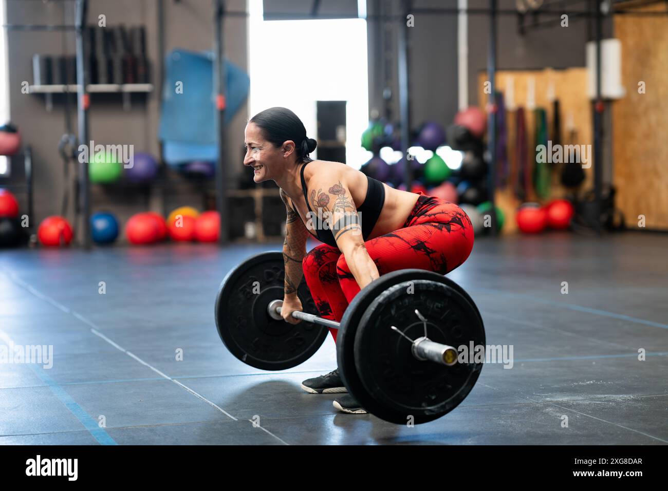 Woman in squat position to lift weight in a gym Stock Photo - Alamy