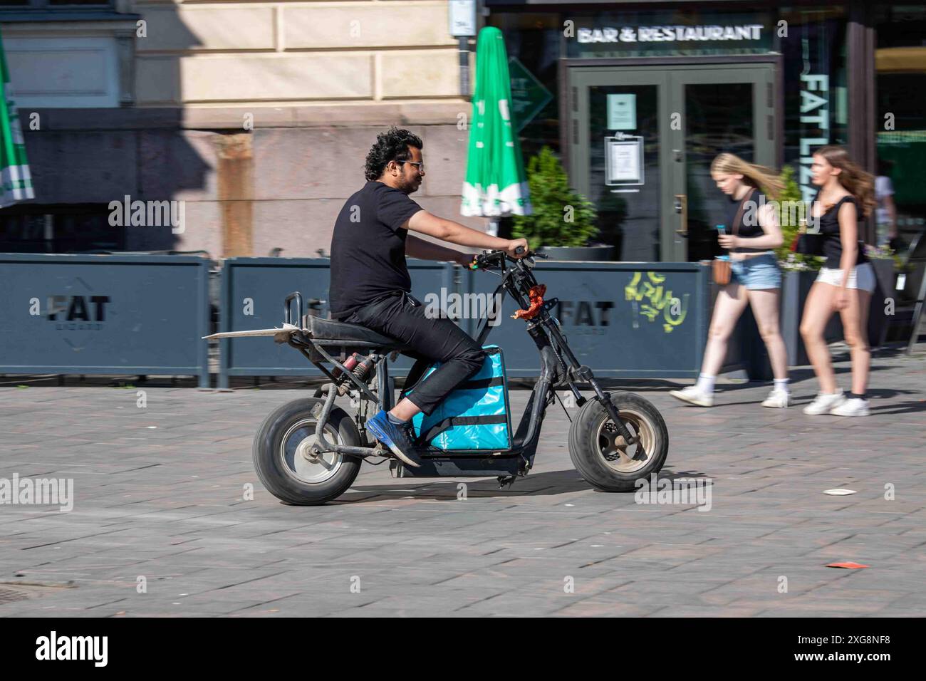 Wolt food courier driving electric moped on Aleksanterinkatu pedestrian ...