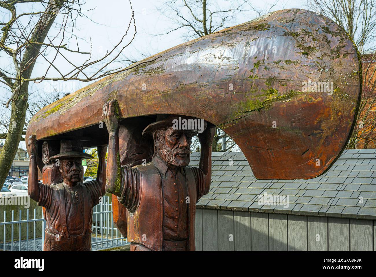 wood carving of two men portaging a canoe, by artist Pete Ryan, Langley ...