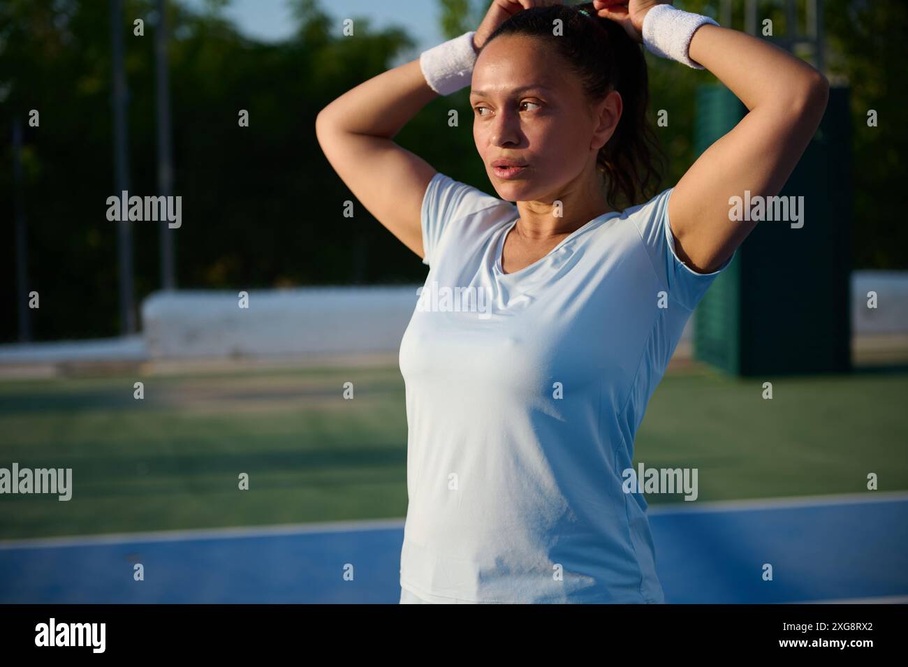 Woman in sports attire, tying her hair, and ready for a workout on an ...