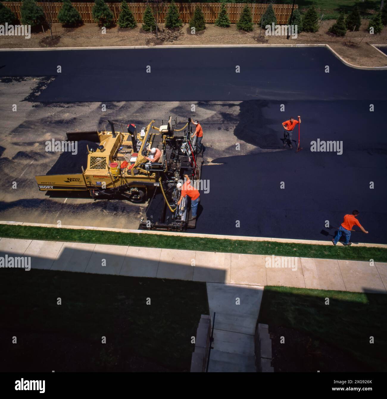 Industrial workers pouring and smoothing asphalt on road Stock Photo ...