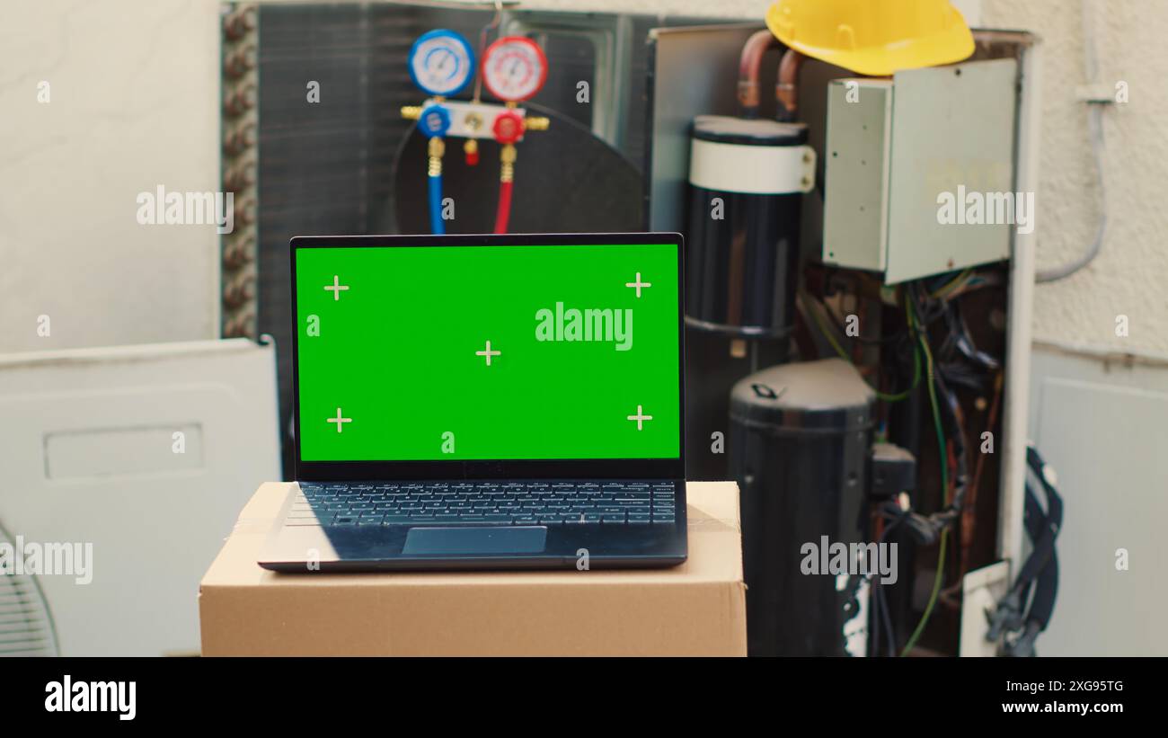 Green screen laptop in front of malfunctioning outdoor HVAC system ...