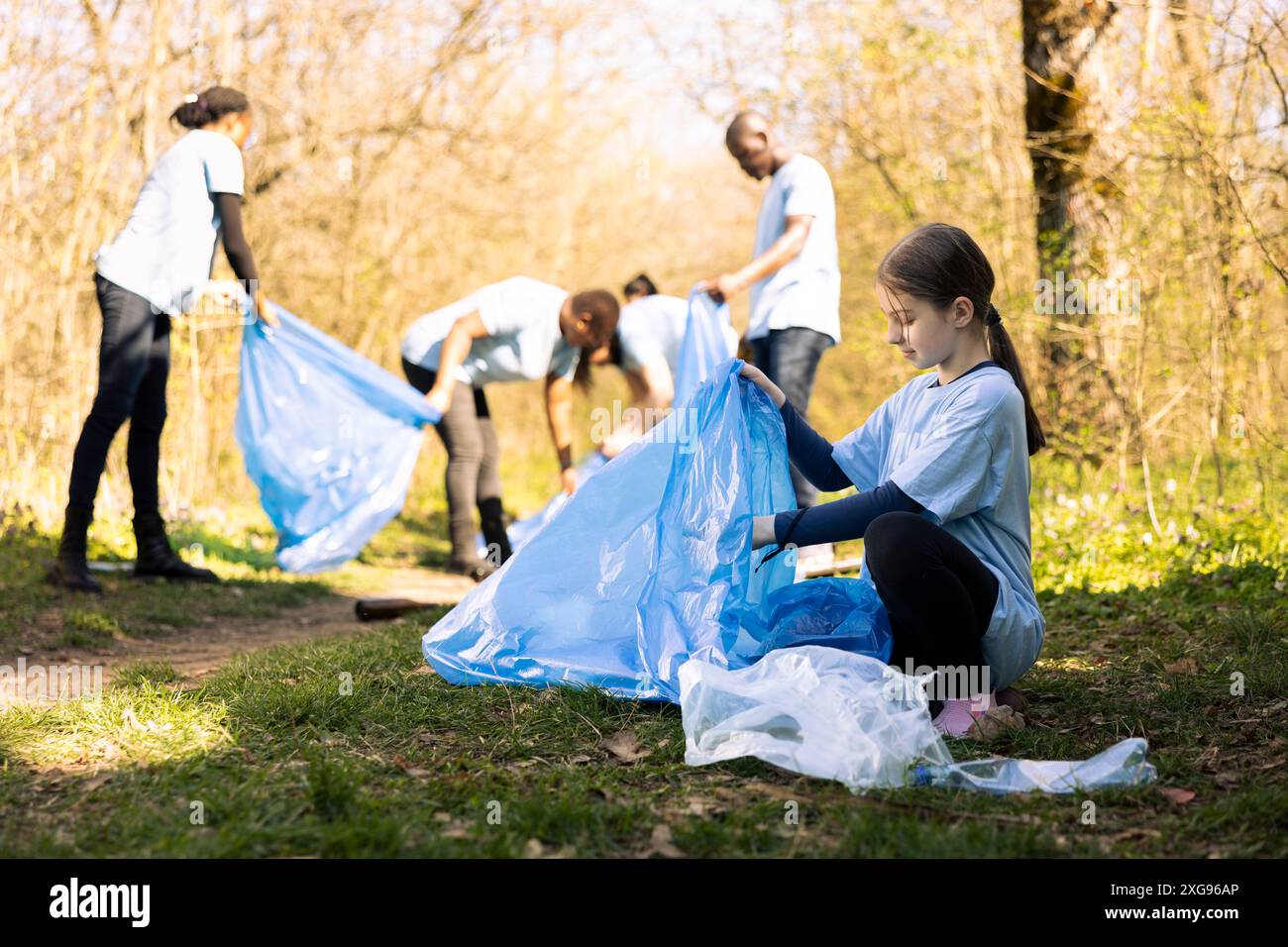 Little girl grabbing waste and plastic junk and collecting in bags ...