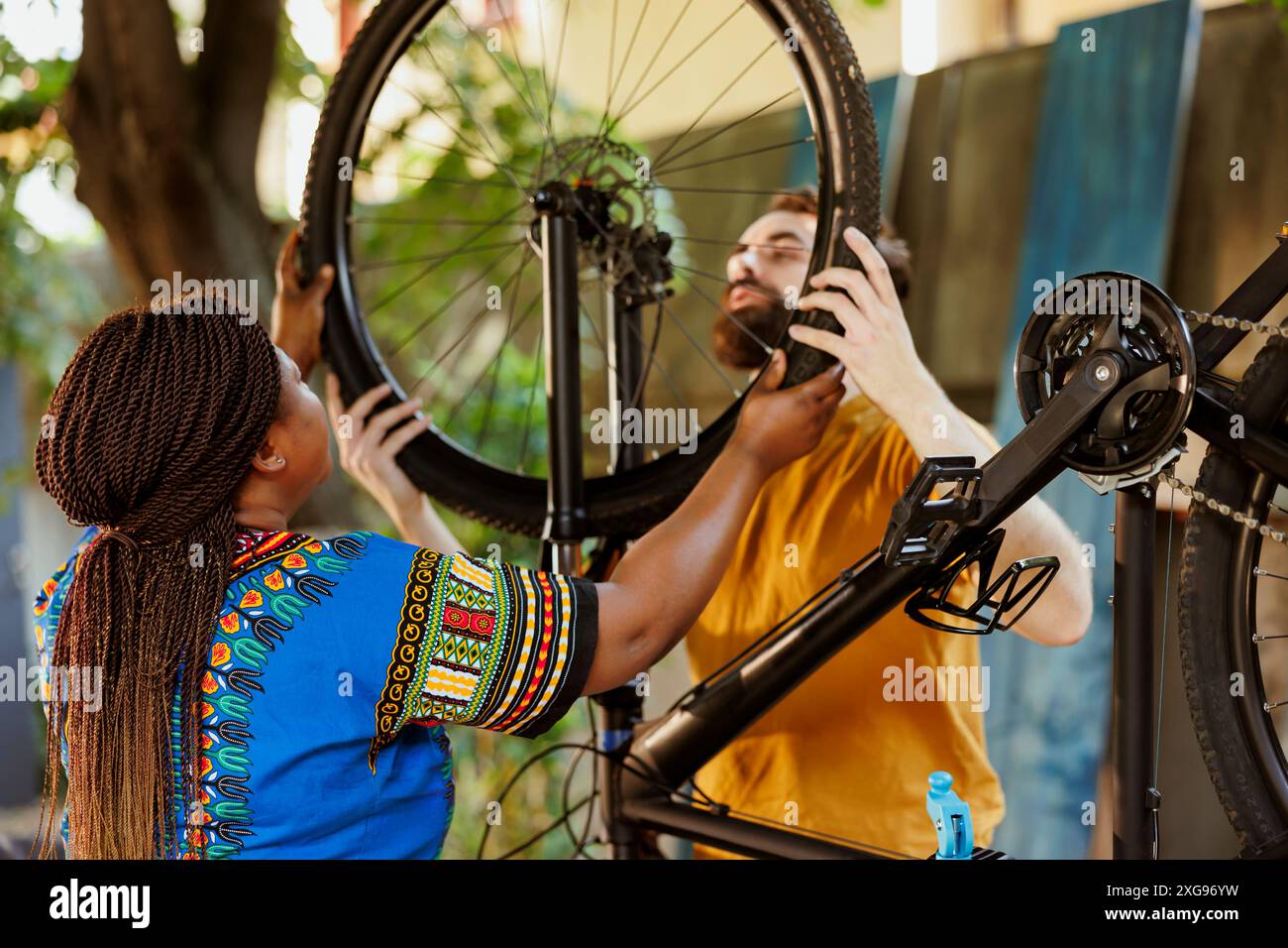 Energetic boyfriend and girlfriend dismantling damaged bicycle tire to ...