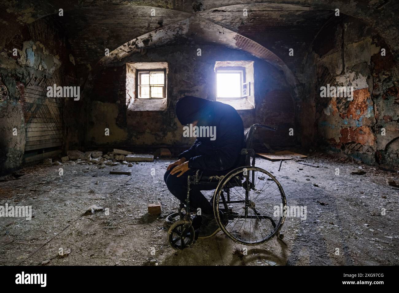 Sad man sitting in old wheelchair in abandoned hospital ward. Person ...