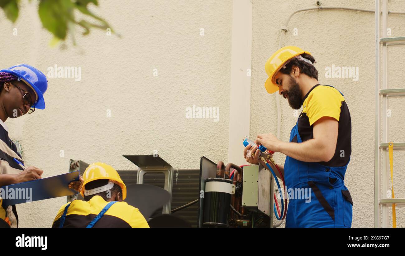 Adept repairmen diverse team working with manifold gauges to check air ...