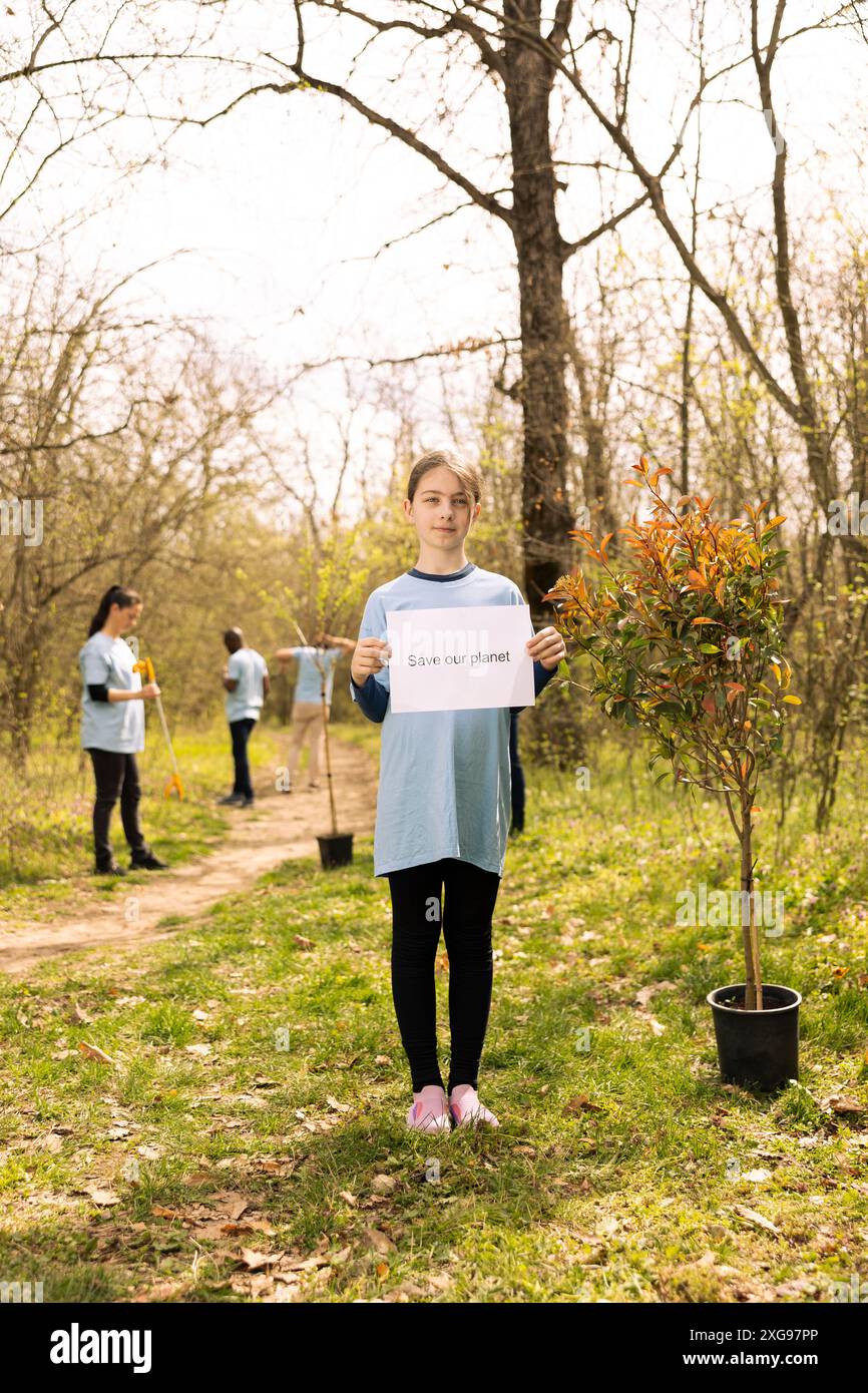Portrait of little girl with save our planet poster against illegal ...