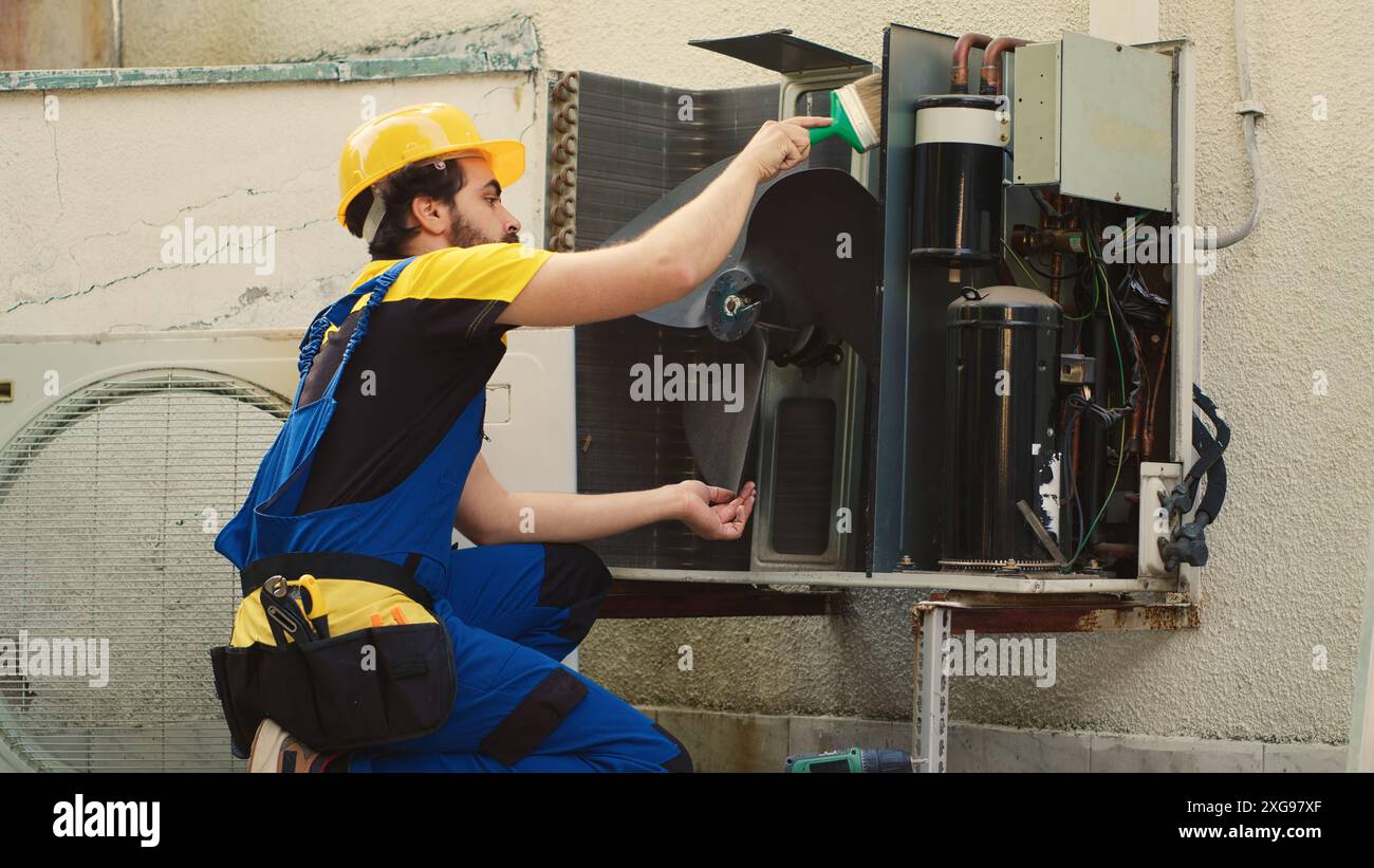 Skilled HVAC engineer removing layer of dust from blower fan to prevent ...