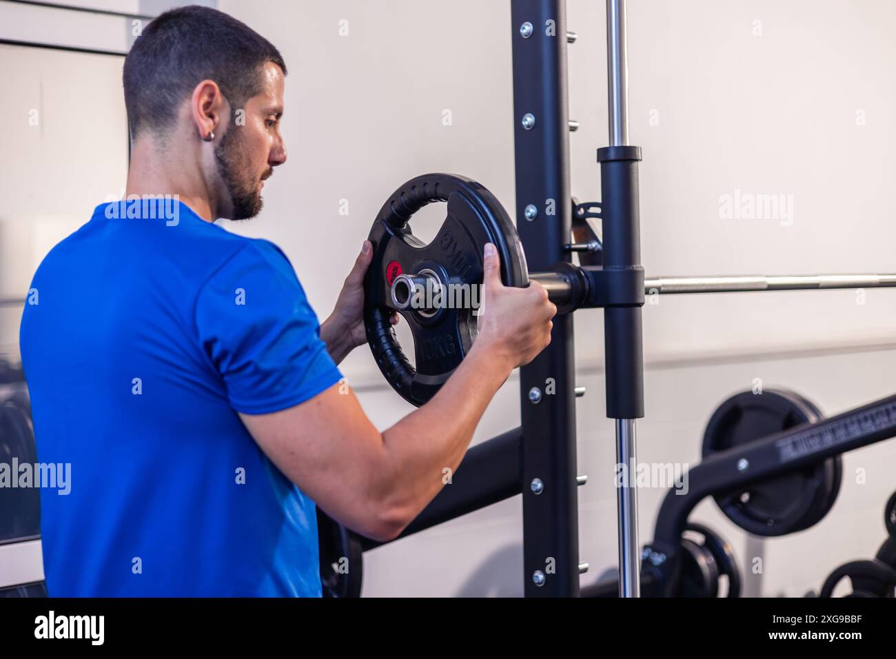 fitness sportsman is seen in a gym setting, focused on preparing his ...