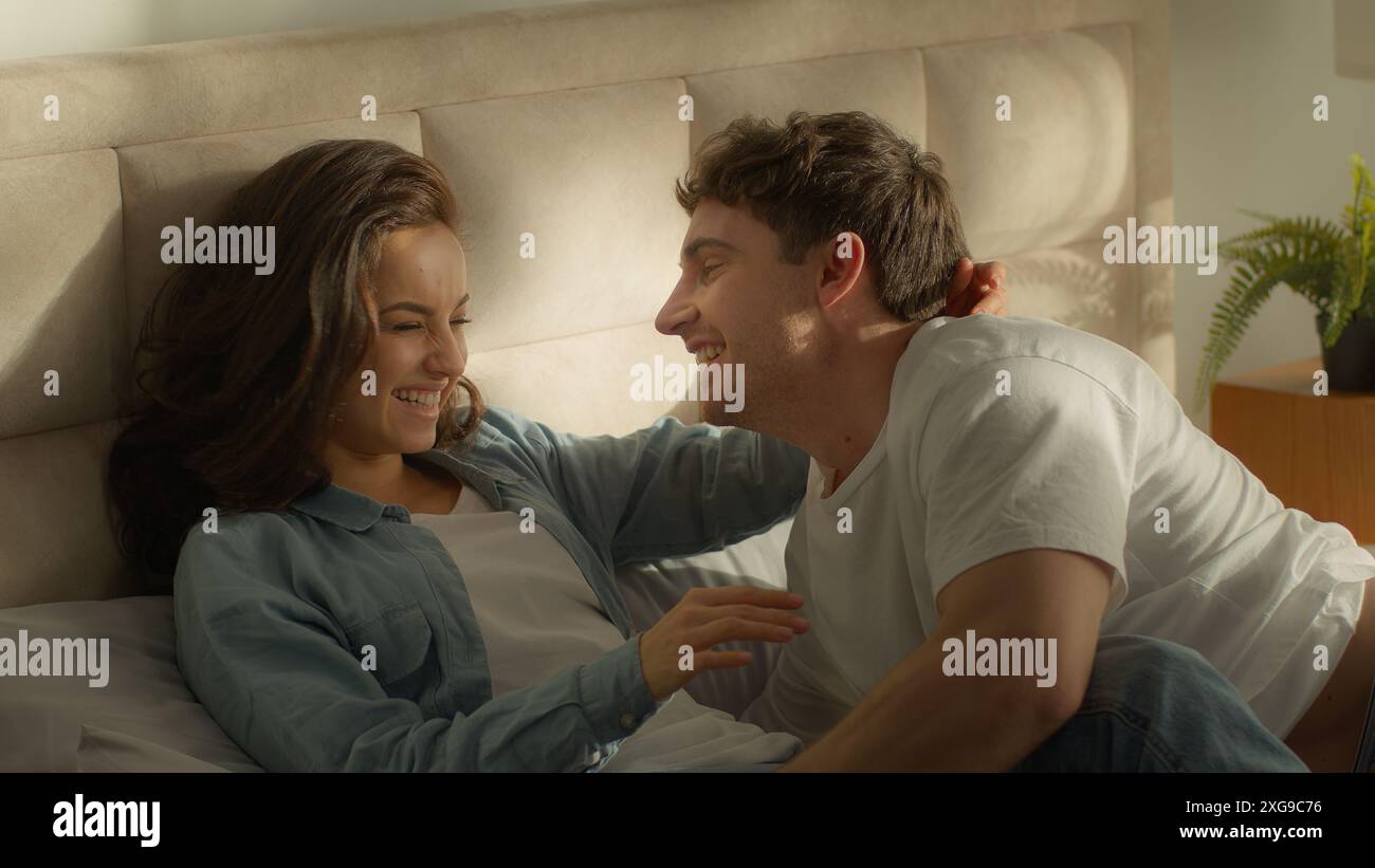 Man falling on bed woman couple female male tickling laughing bedroom ...