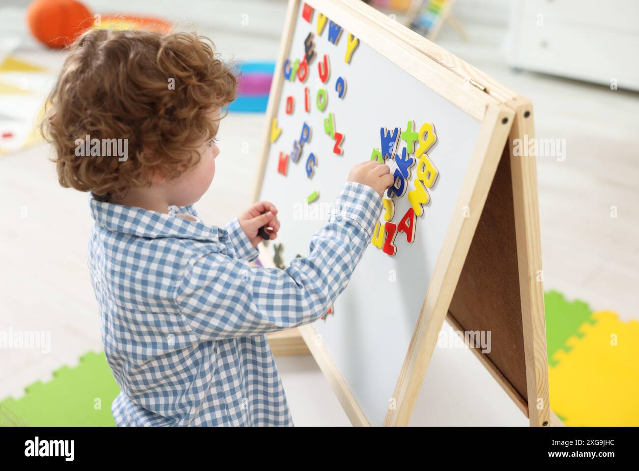 Cute little boy learning alphabet with magnetic letters on board in ...