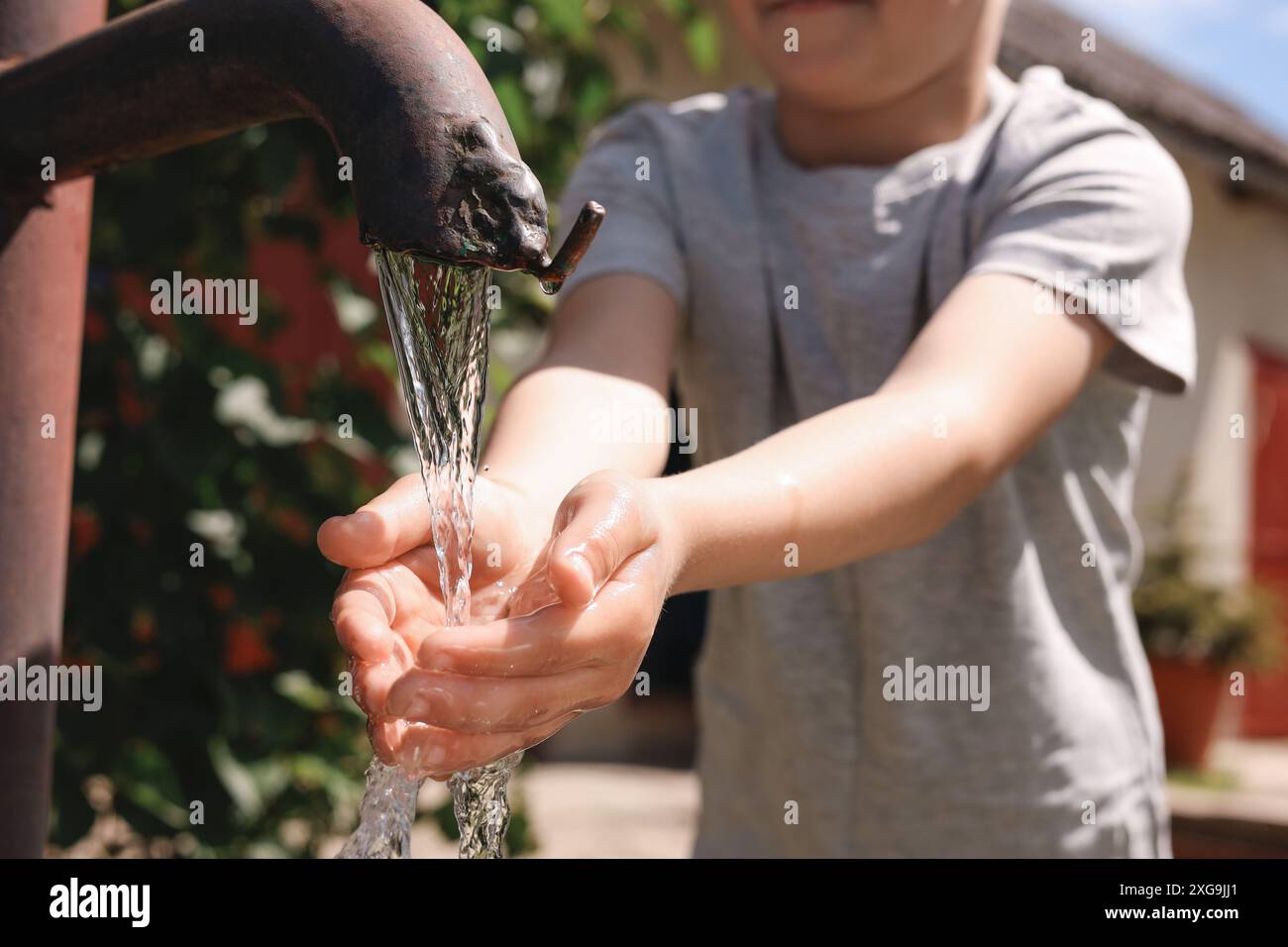 Water scarcity. Little boy drawing water with hands from tap outdoors ...