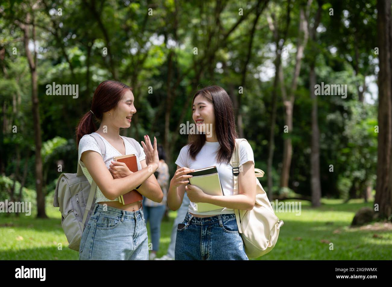 Two pretty and happy young Asian female college students with backpacks ...