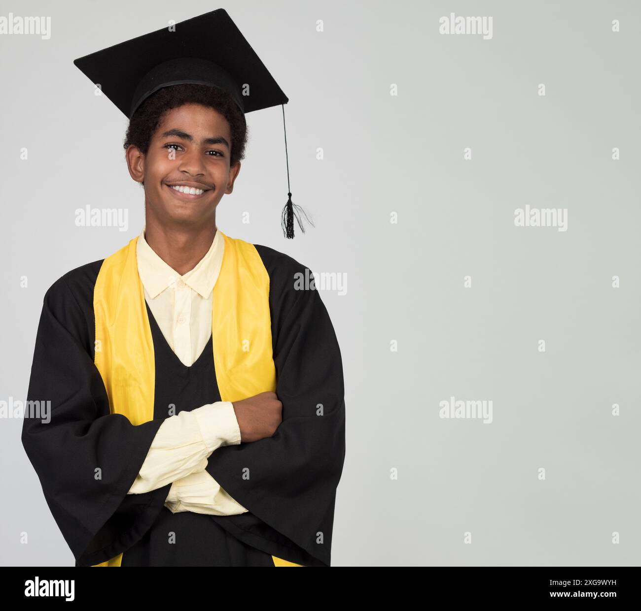 Portrait of graduate teen latin boy student in black graduation gown ...
