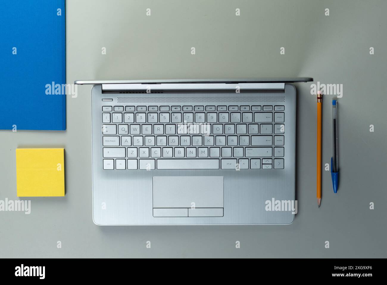 Workspace shown from top with laptop, sticky notes, stationery on gray ...