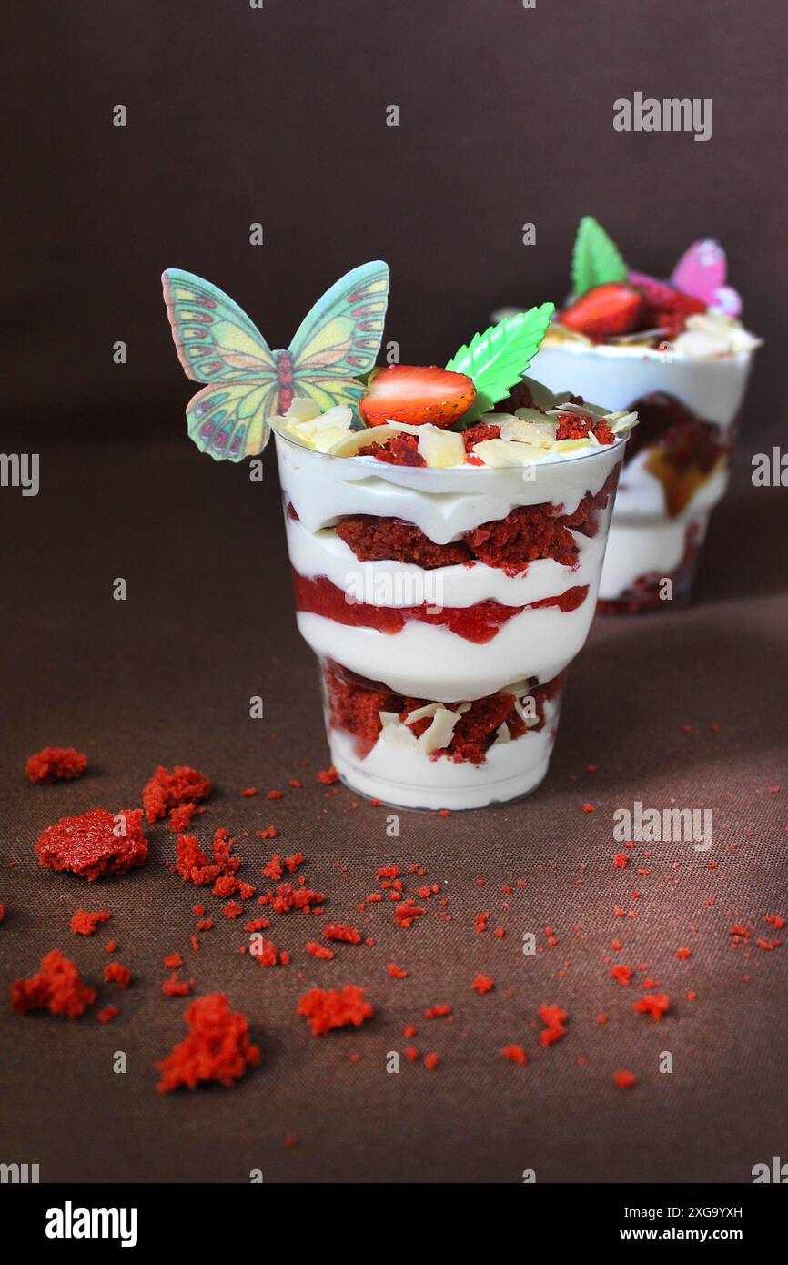 Two parfaits made with red velvet cake and whipped cream, adorned with ...