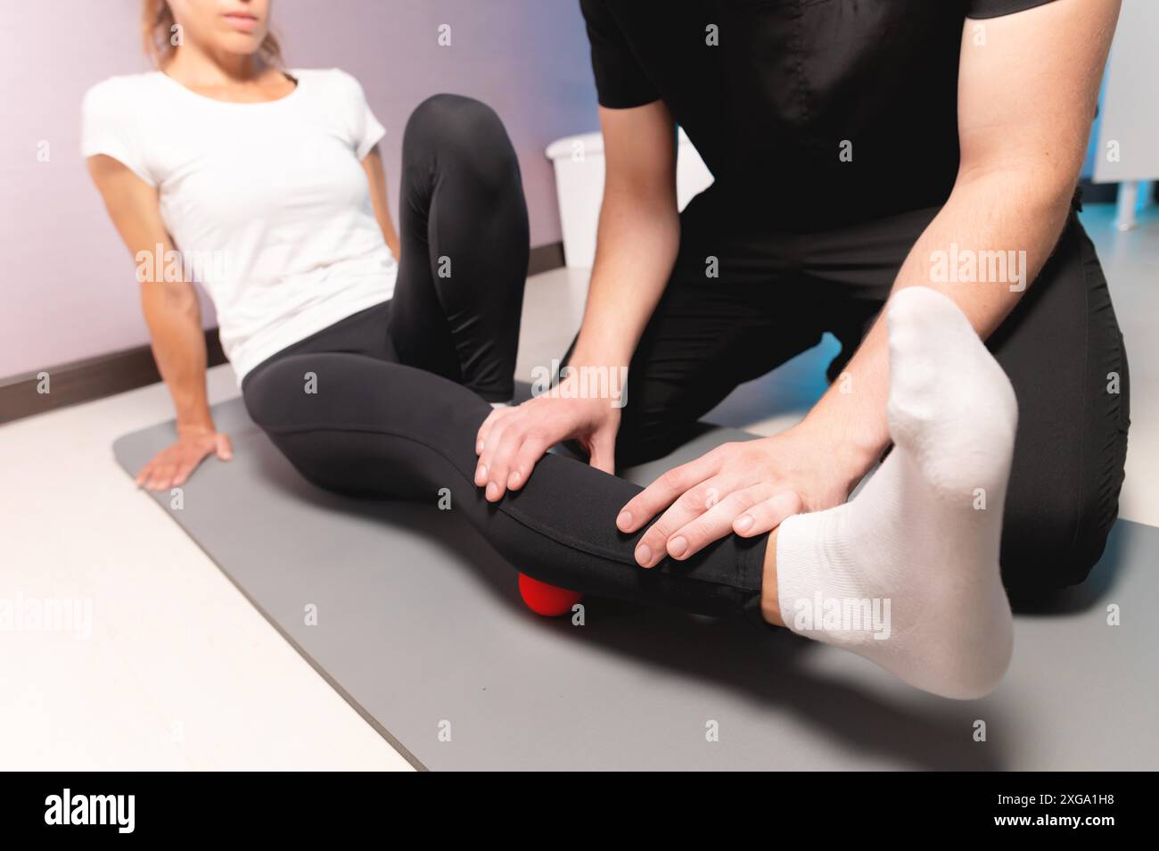 Physiotherapist teaches self-massage with red balls, patient with leg ...