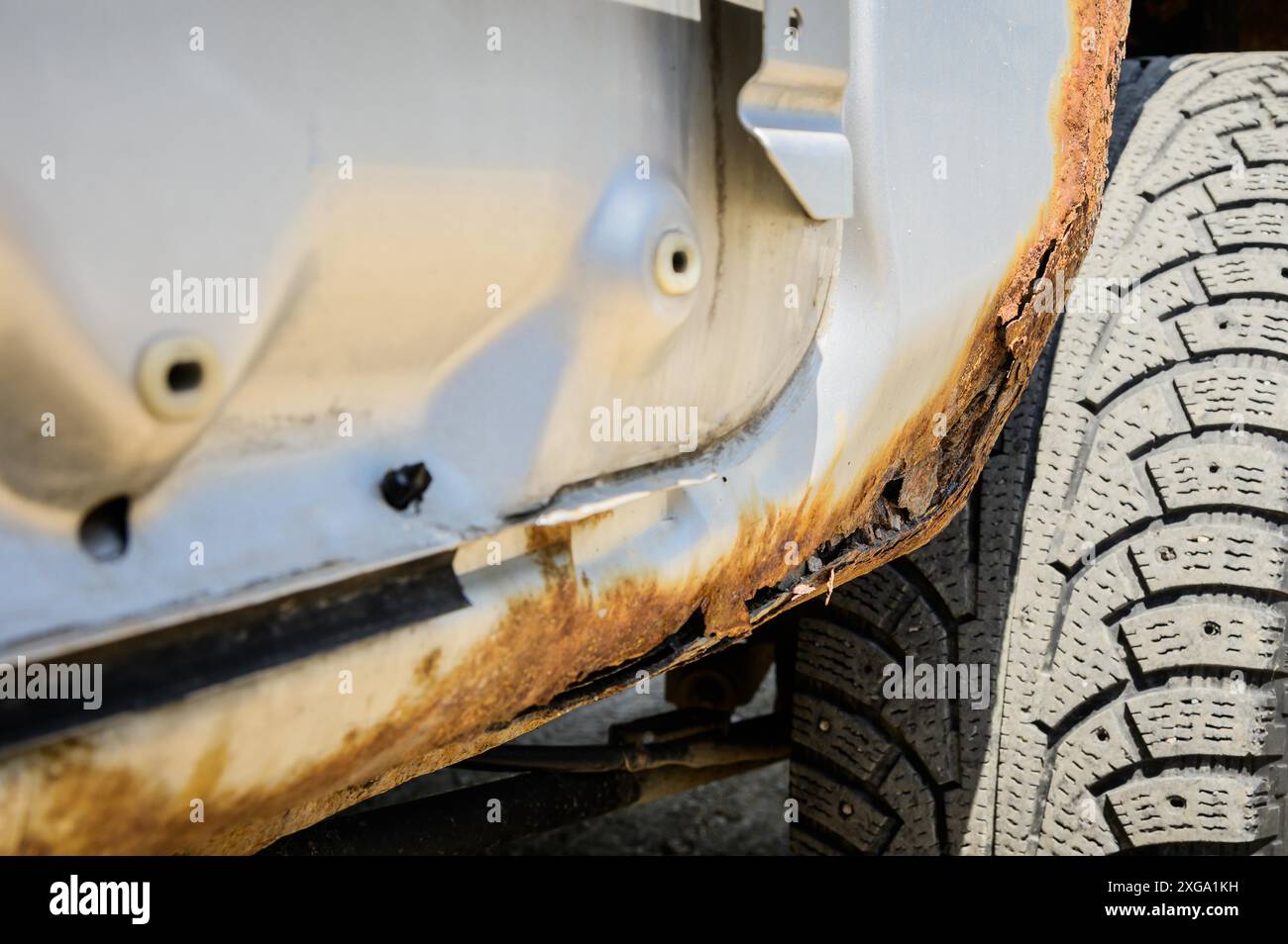Rusty part of the car body with through-out corrosion. Background for ...