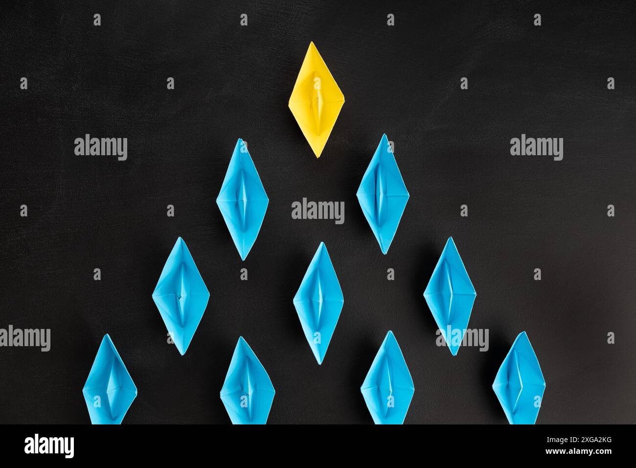 Leadership concept. Group of paper boat on blackboard background. One ...