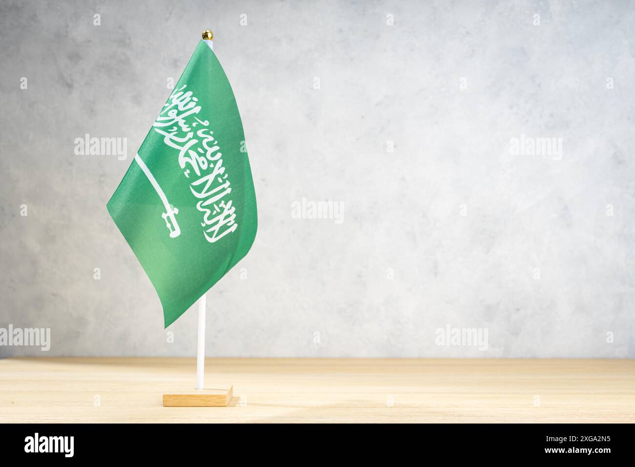 Saudi Arabia table flag on white textured wall. Copy space for text ...