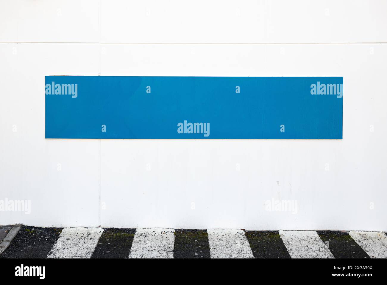 Blank blue sign placed on white wall on the outside of building ...