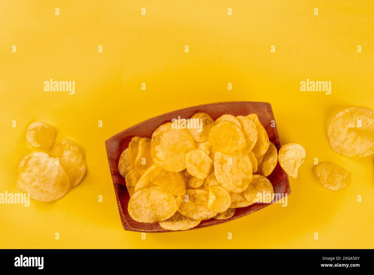 Potato chips or crisps, a salty snack in a bowl, top shot on a yellow ...