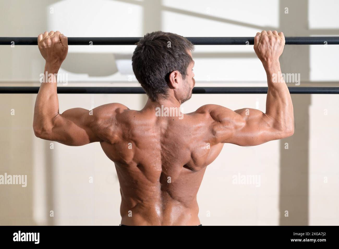 Athlete doing pull-ups at the gym. Handsome man doing functional ...