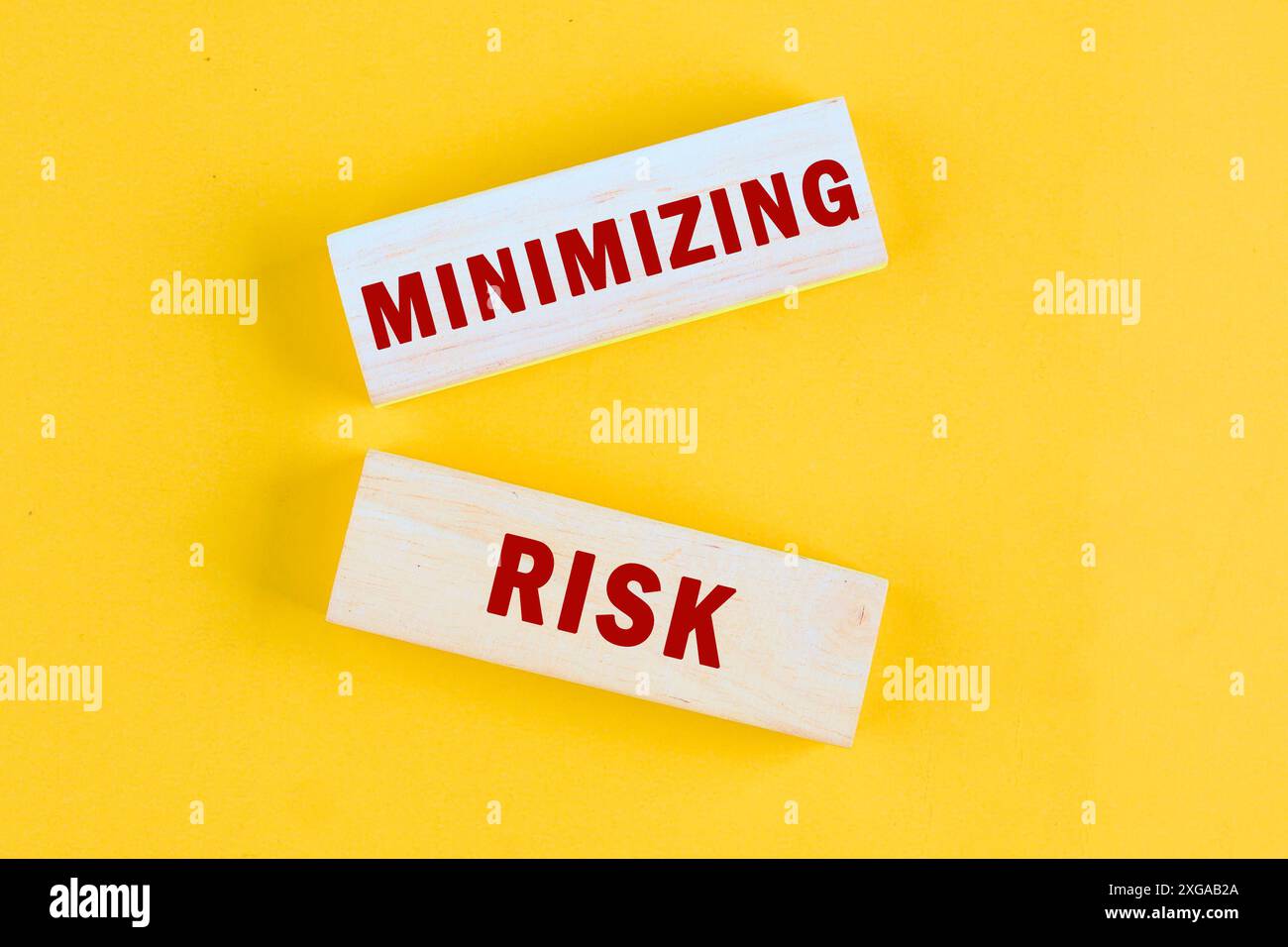 MINIMIZING RISK text on wooden blocks on a light mustard background ...