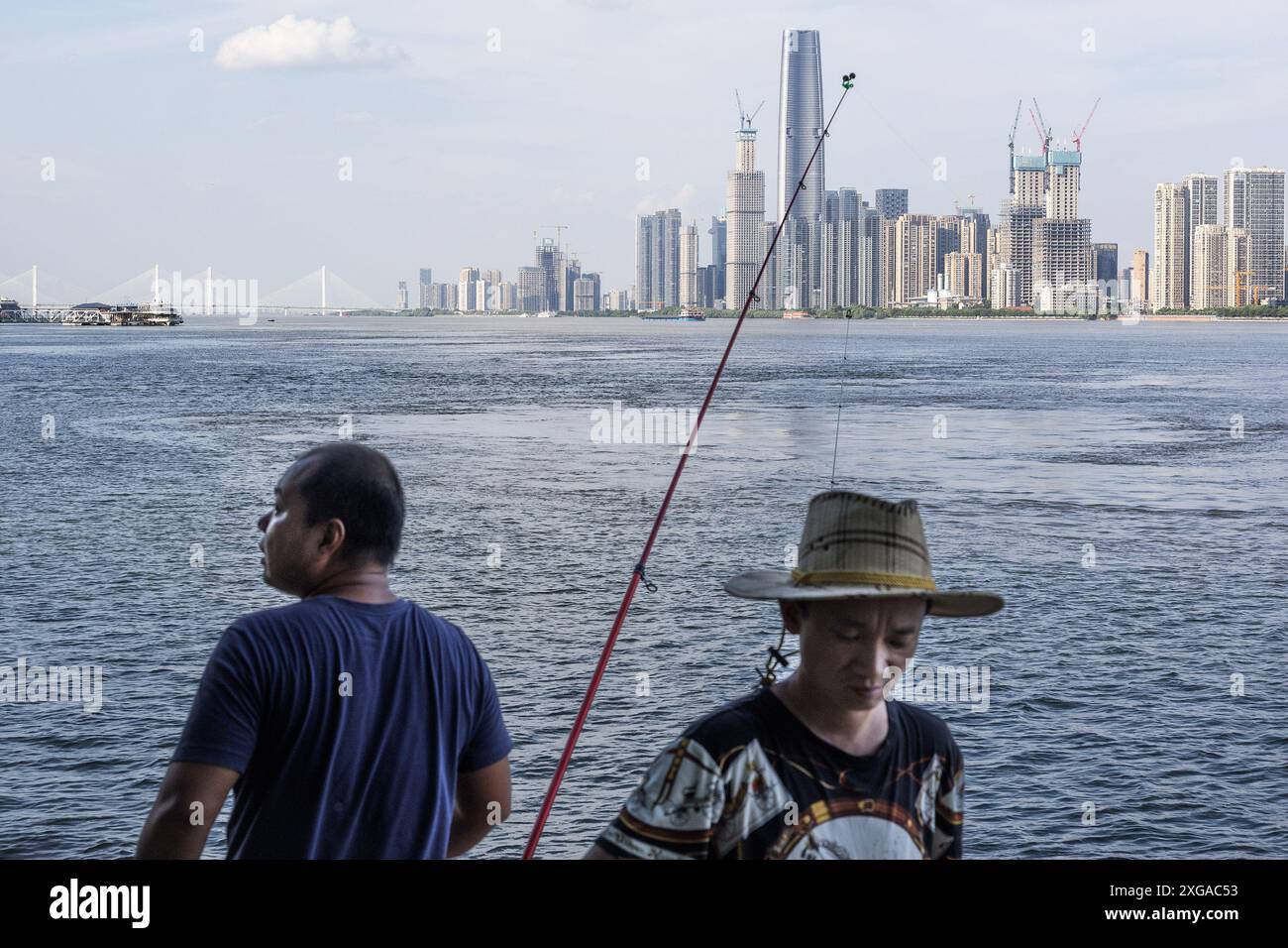 Wuhan, China. 07th July, 2024. Two men seen fishing in the flooded ...