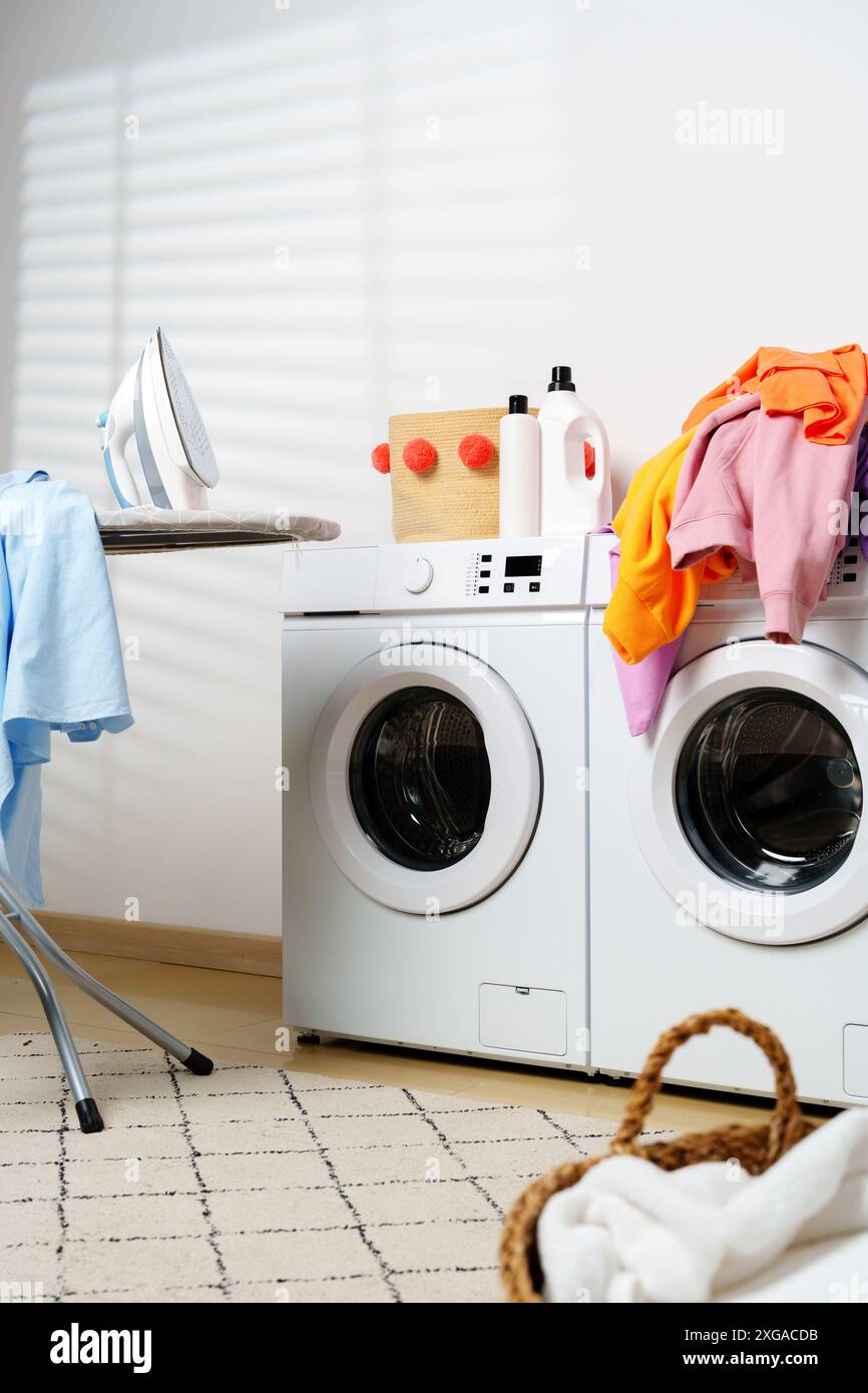 Modern Laundry Room With White Washing Machines, Ironing Board, and ...