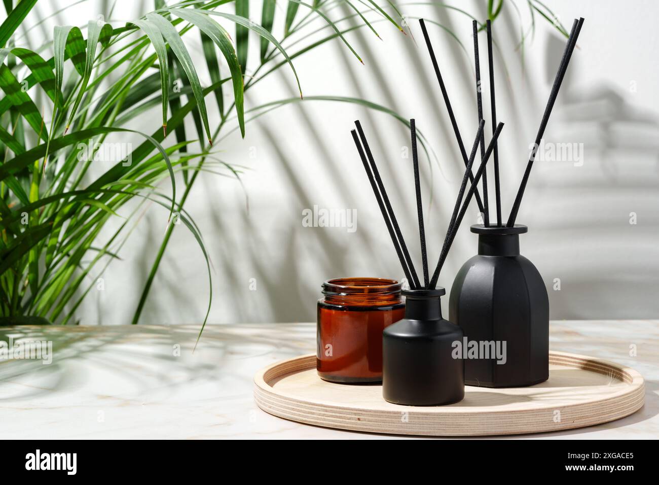 Black Reed Diffuser, Amber Candle, and Wooden Tray on White Surface ...
