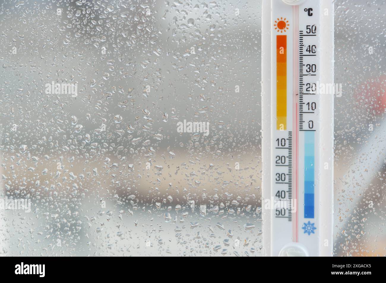 Thermometer Attached to Window With Rain and Plant Stock Photo - Alamy