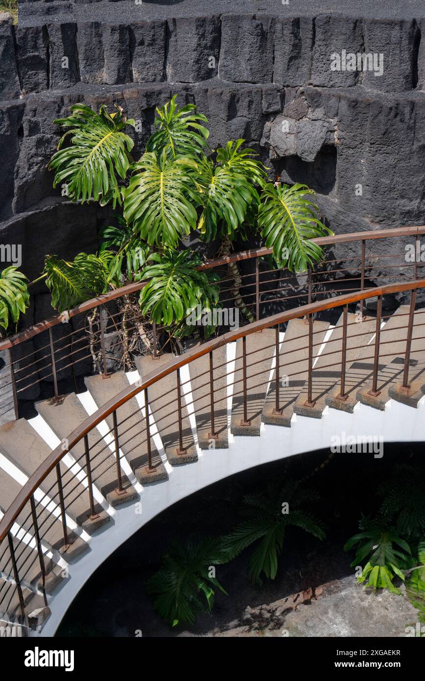 A white, circular staircase with a metal railing winds its way up ...