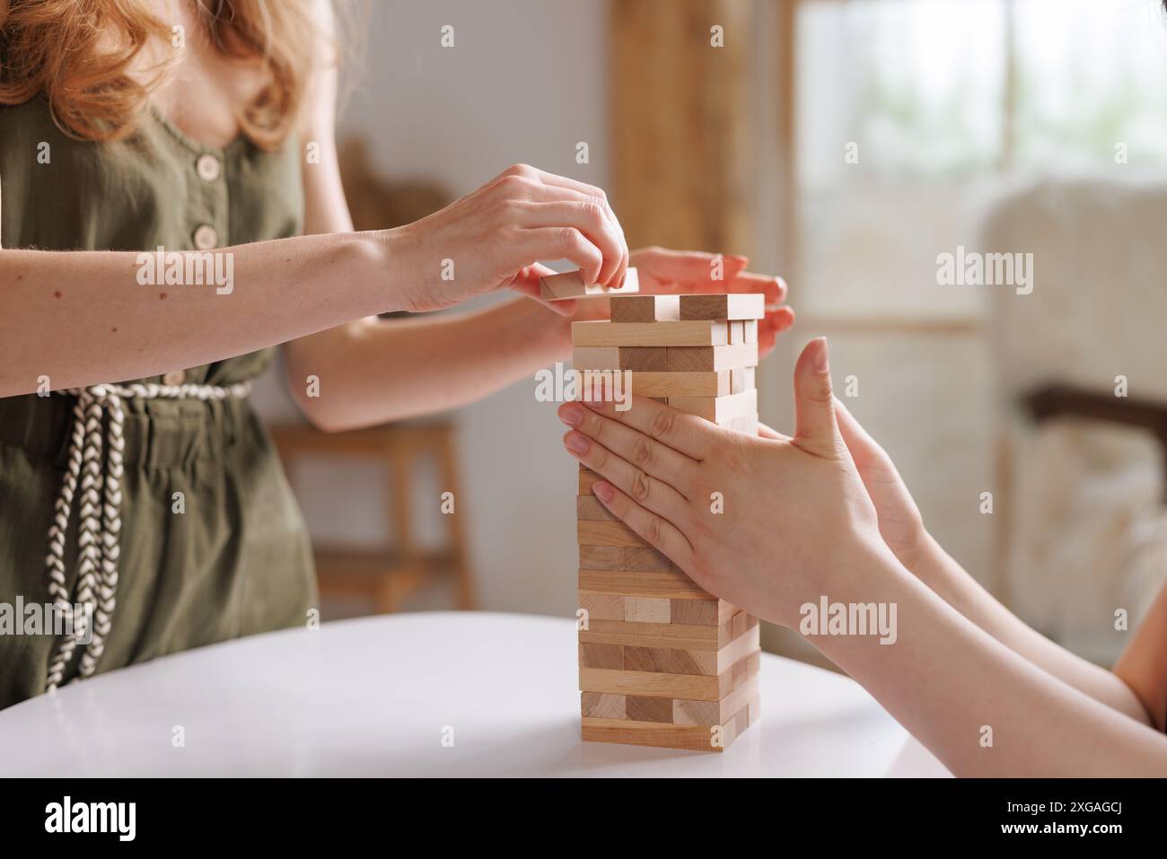 two women playing a board game made of wooden blocks at home ...