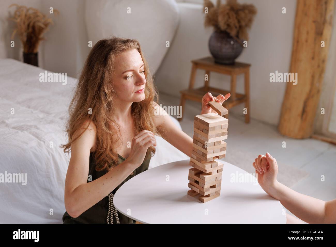 two women playing a board game made of wooden blocks at home ...