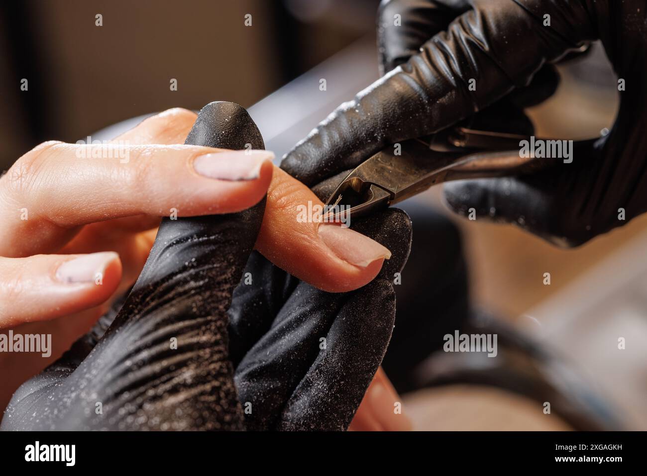 A manicurist gives a hardware manicure to a client using special tools ...