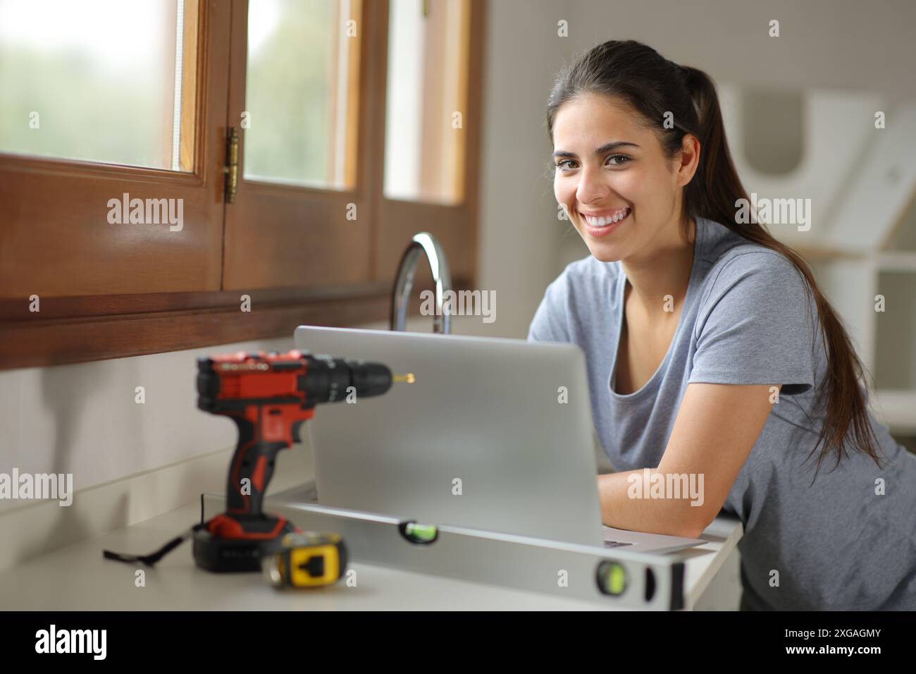 Happy homeowner reforming house using laptop looks at you Stock Photo ...
