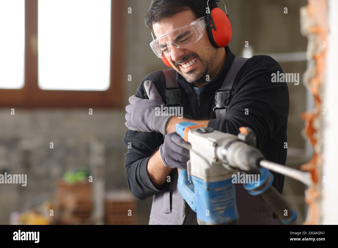 Construction worker suffering arm ache using rotary hammer in a house ...