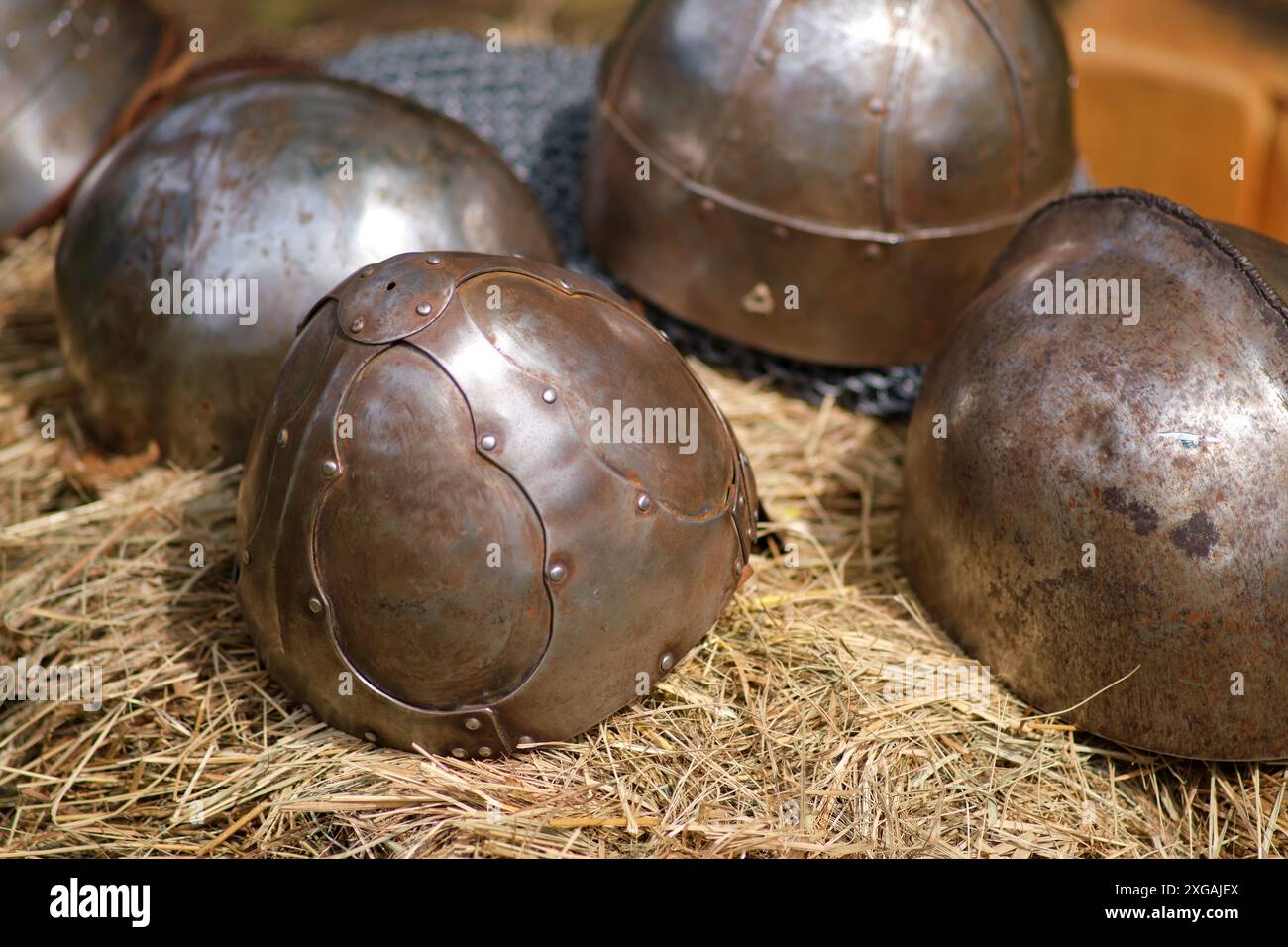A collection of old metal helmets are sitting on a hay bale. The ...