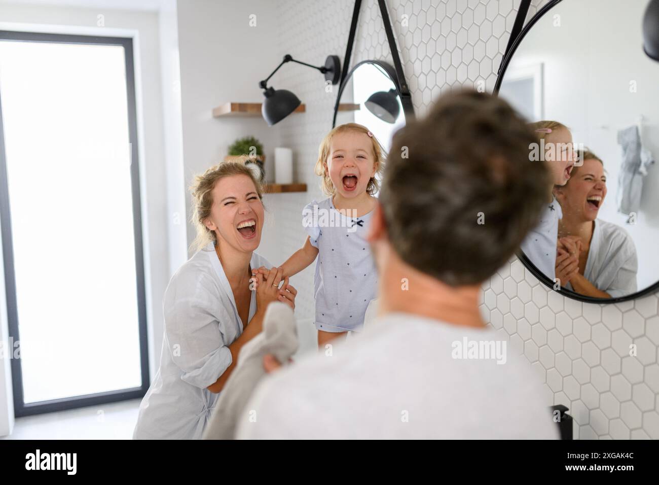 Parents and daughter having morning bathroom routine, brushing teeth ...