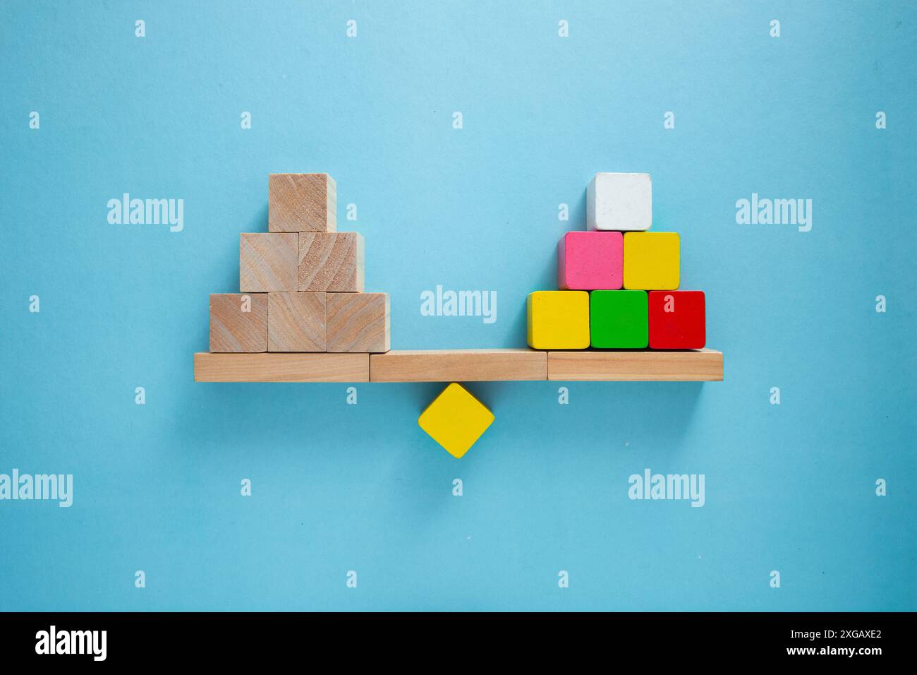 Single red block is outweighing a stack of wooden cubes on a seesaw ...