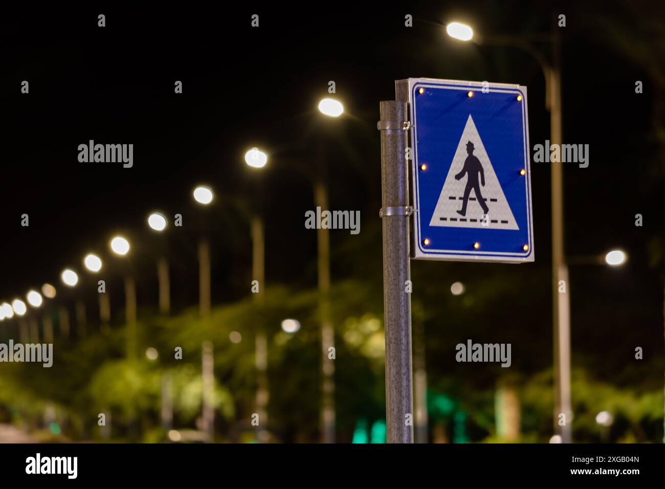 Illuminated pedestrian crossing sign at night. City street lightning ...