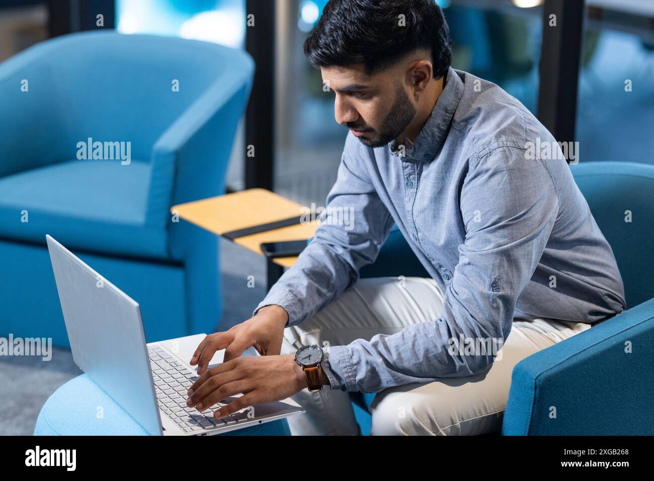 Typing on laptop, man working in modern office environment, focusing on ...